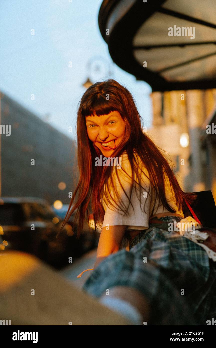 Happy young imp woman shows tongue on city street Stock Photo - Alamy