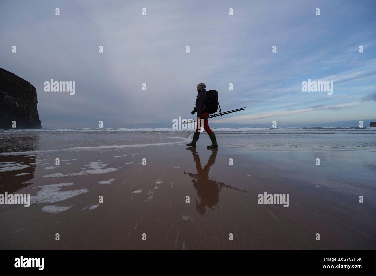 Photographer walks across beach at Rackwick bay, Hoy, Orkney, Scotland ...