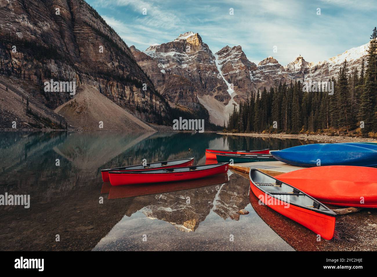 Colorful canoes on Moraine lake shore with mountains in background ...
