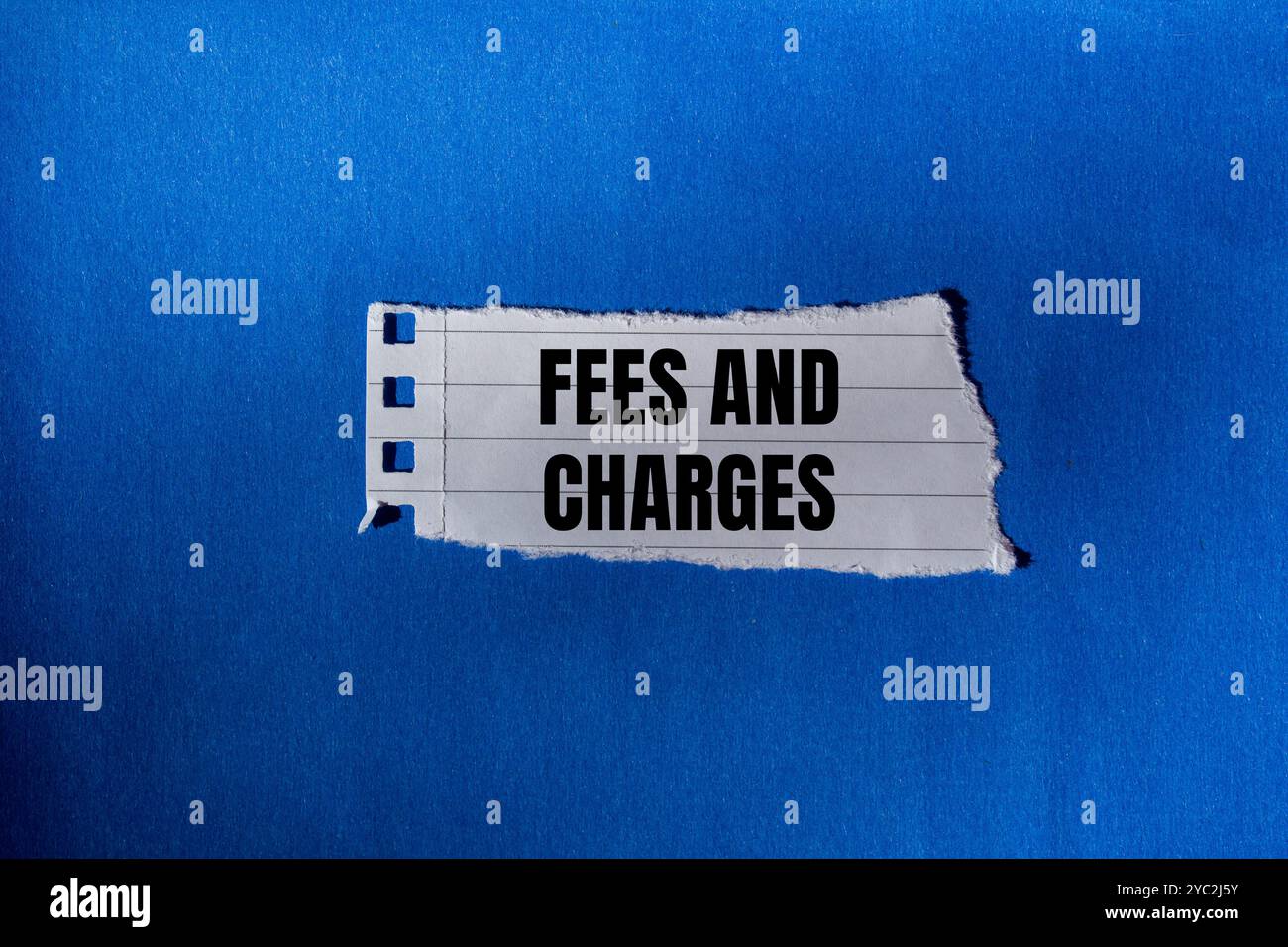 Fees and charges message written on ripped torn paper piece with blue ...