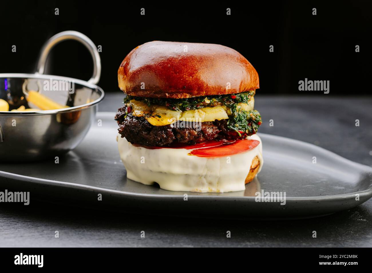 Gourmet burger with grilled pineapple, herb topping, and fries, perfect ...