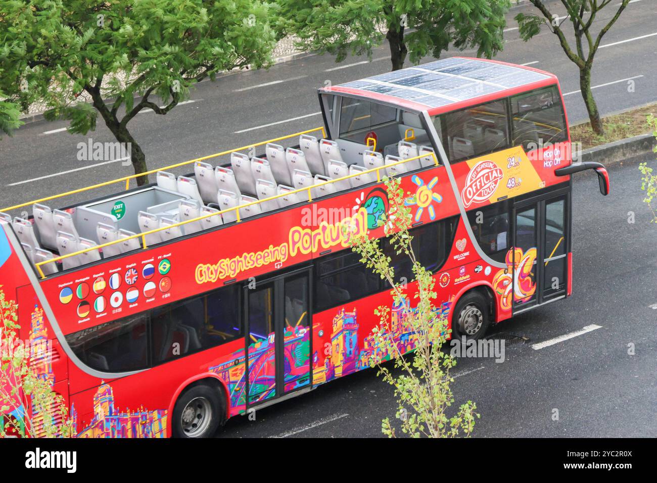 Bright red city sightseeing double decker bus driving down the street ...