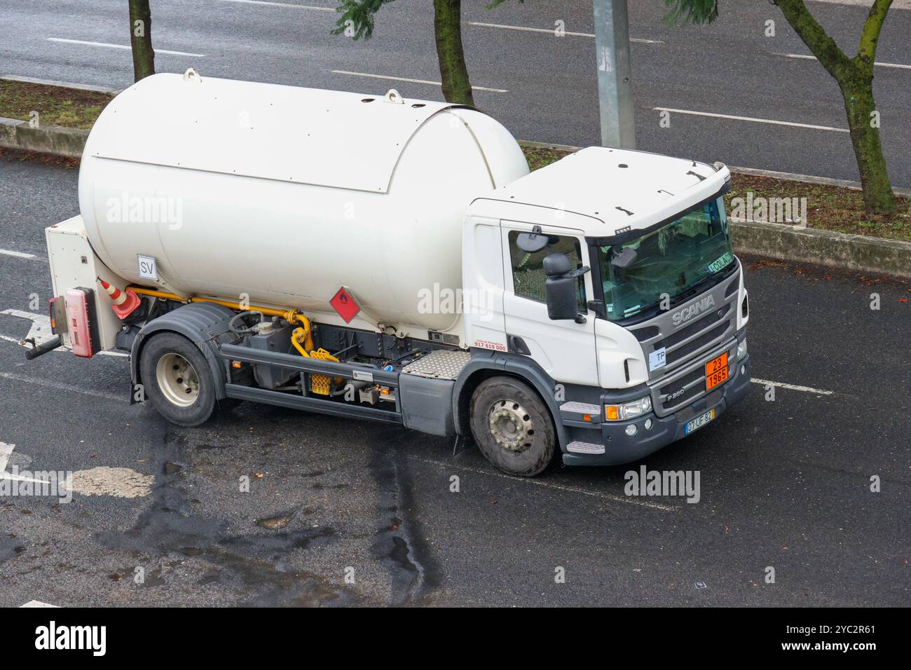 White fuel tank truck driving on a highway, transporting flammable ...