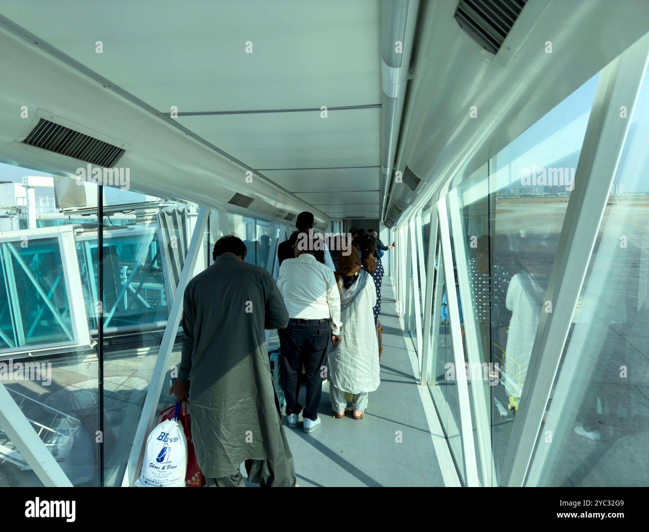 Passengers inside boarding bridge, view from the back of people going ...