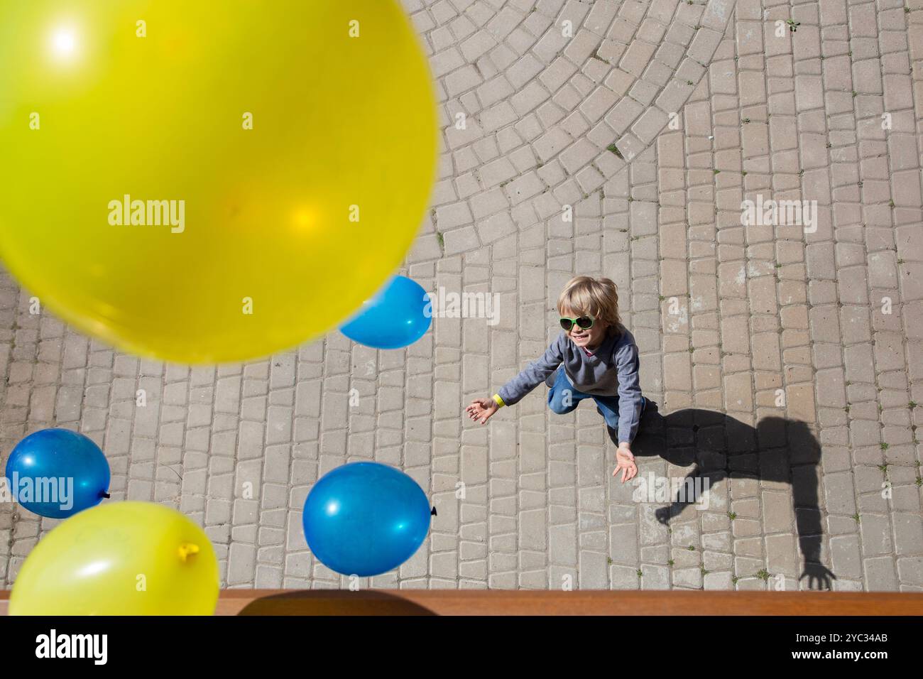 Many yellow and blue balloons are flying at the boy from above Stock ...