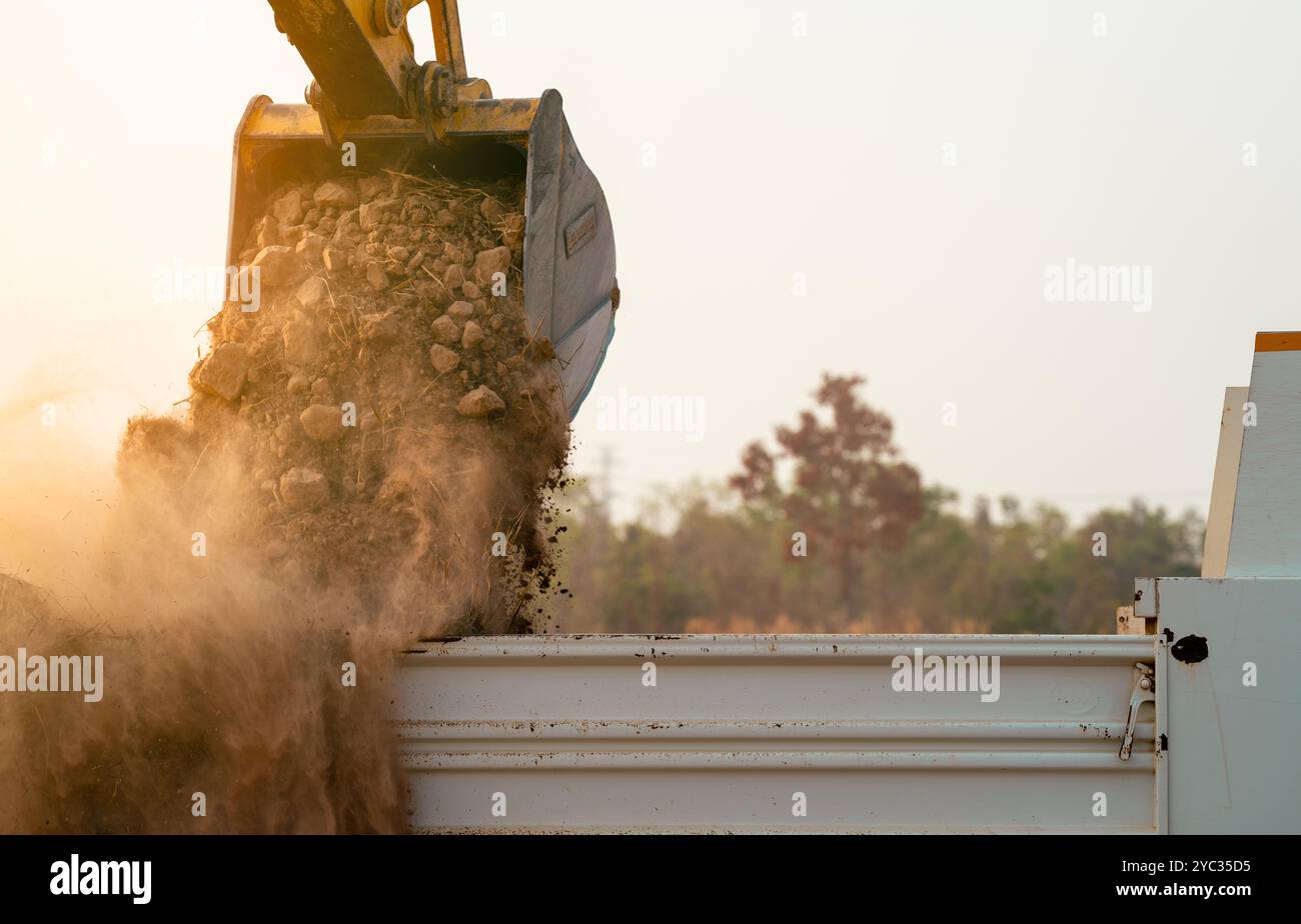Backhoe loading soil into heavy duty dump truck at construction site ...