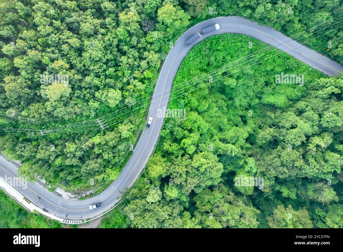 Aerial view car and truck driving on winding road through green forest ...