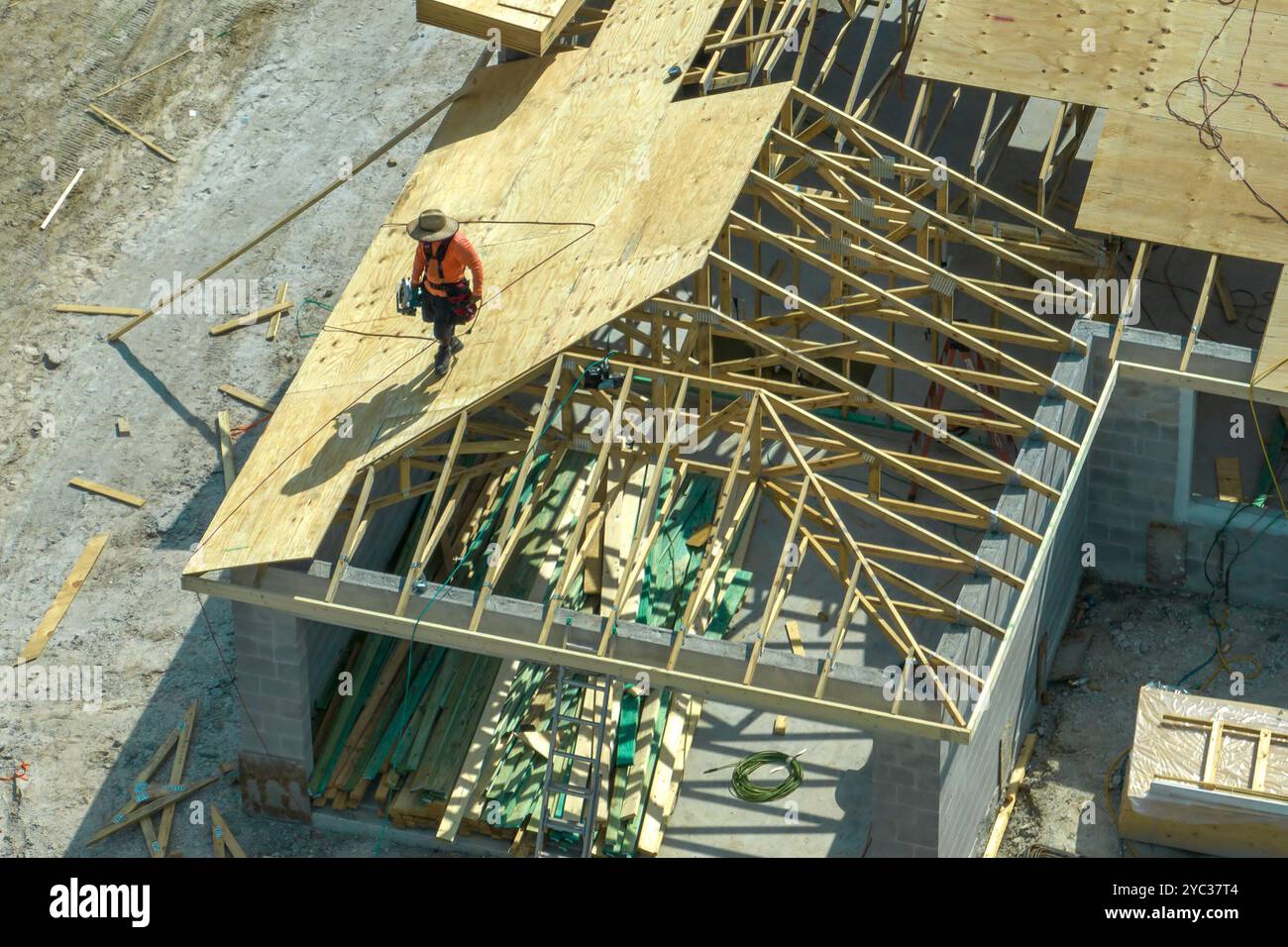 Builders working on roof construction of unfinished residential house with wooden frame ...