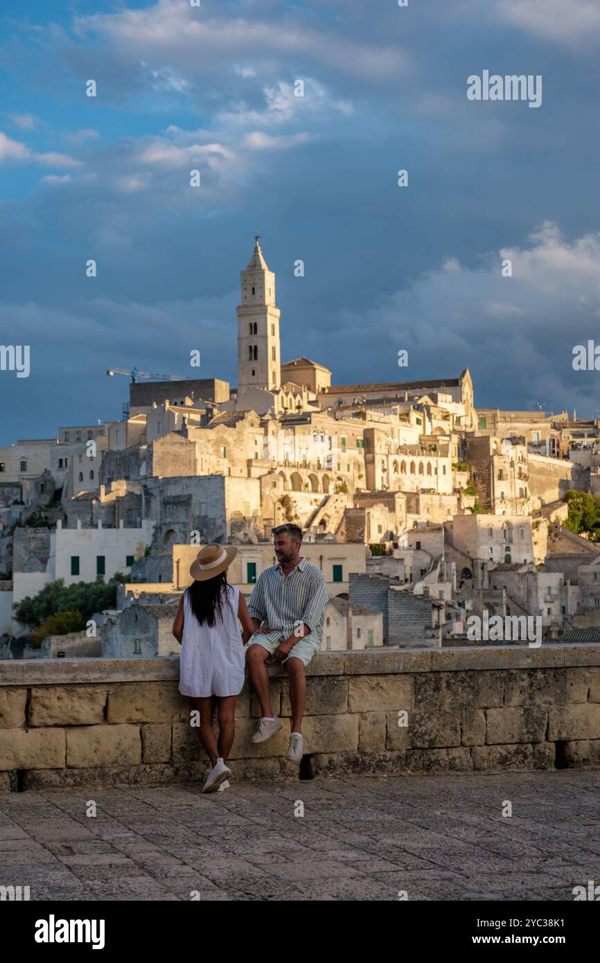 A couple sits on a stone wall, soaking in the warm sunset glow over the ...