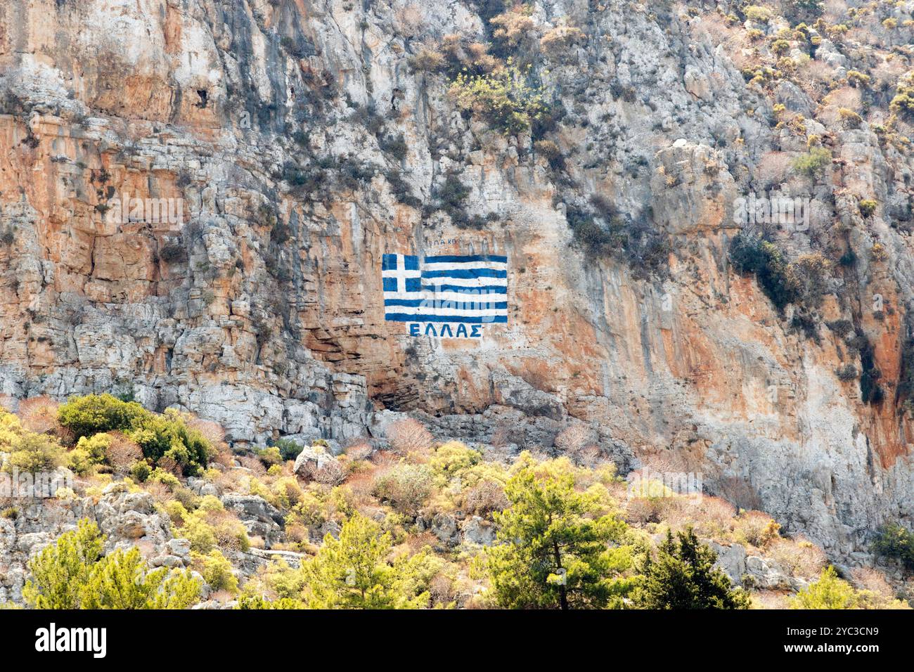 A Greek flag painted on a cliff face with the words Greece written in ...