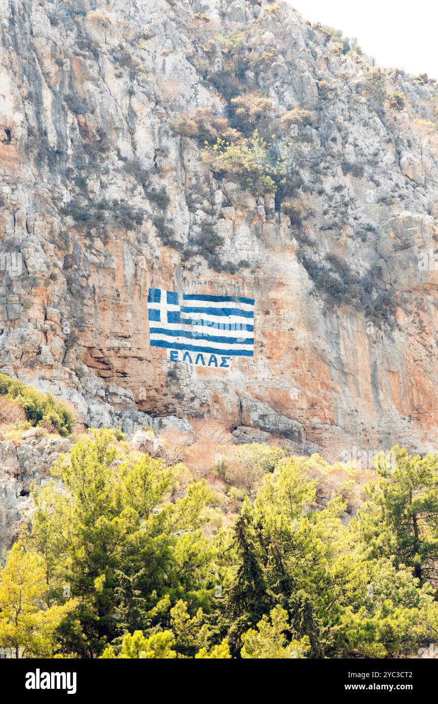 A Greek flag painted on a cliff face with the words Greece written in ...