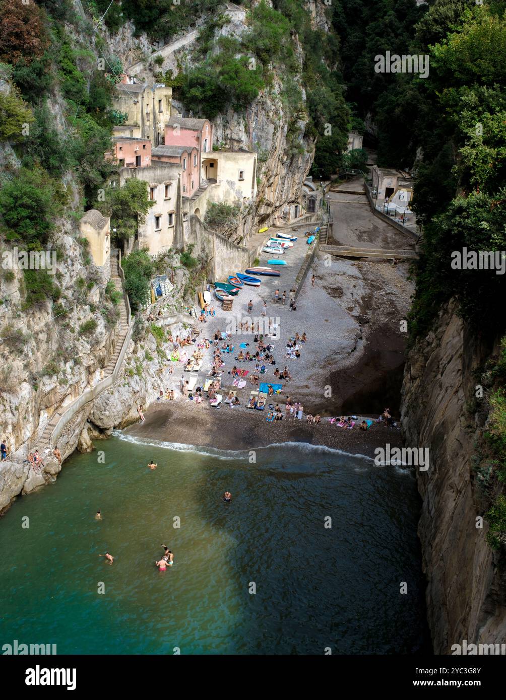 Basking in the warmth of the Italian sun, visitors relax on the pebble ...