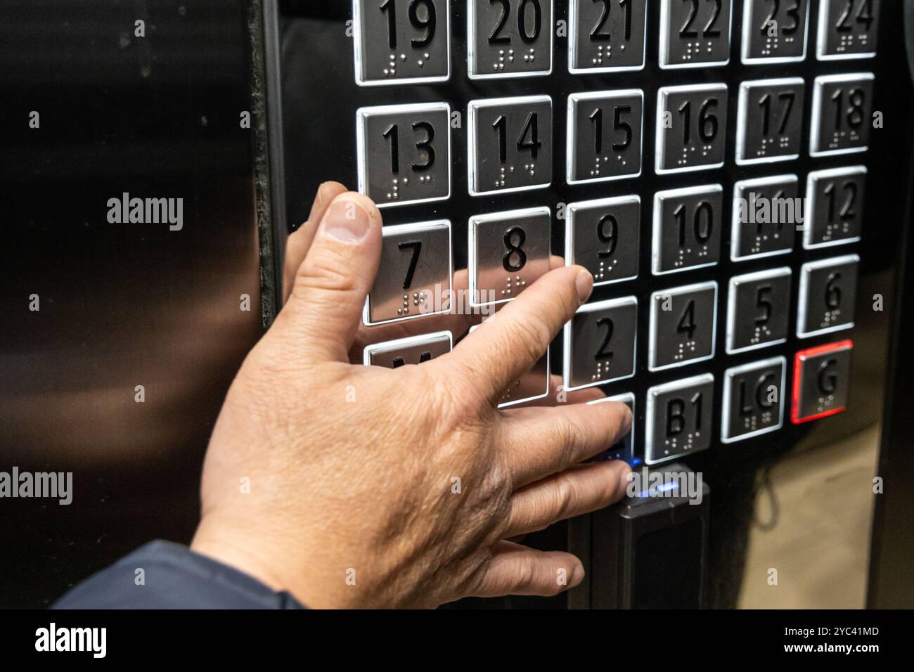 Hand reaching out to elevator panel's braille codes to press button for ...