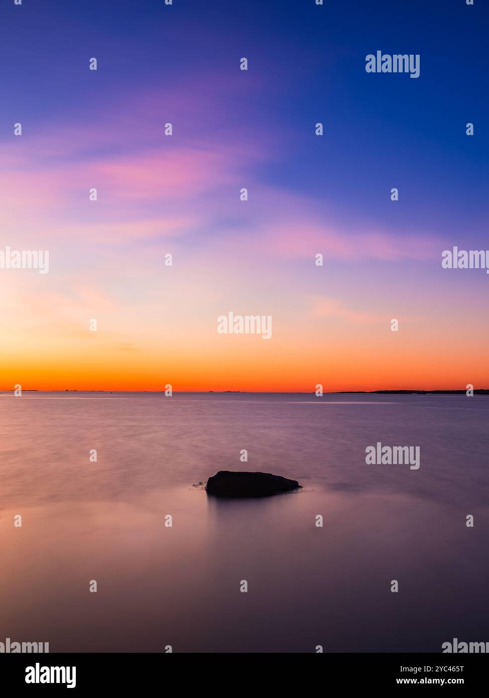 The sun sets over a serene body of water, painting the sky with vivid ...