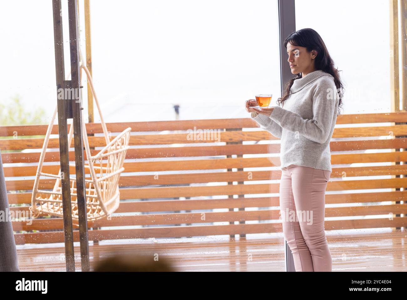 Woman enjoying hot tea by window on cozy rainy day at home Stock Photo ...
