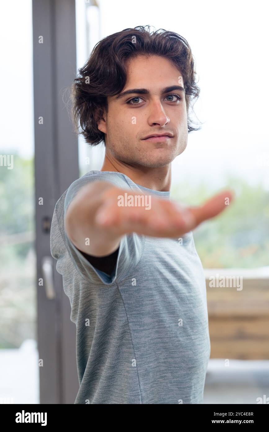 Young man practicing yoga at home, focusing with outstretched arm Stock ...