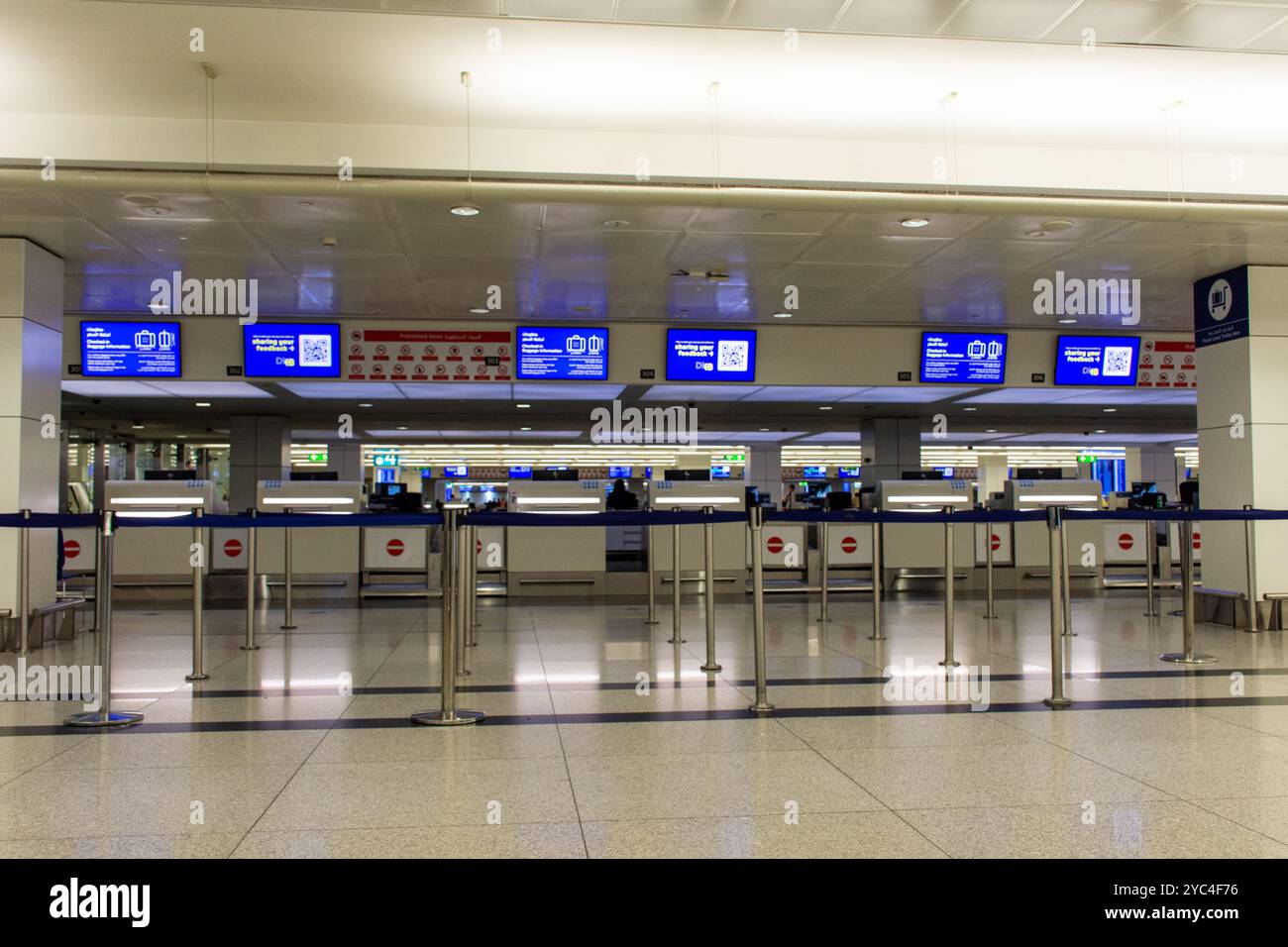 An empty airport check-in area with multiple counters and digital ...