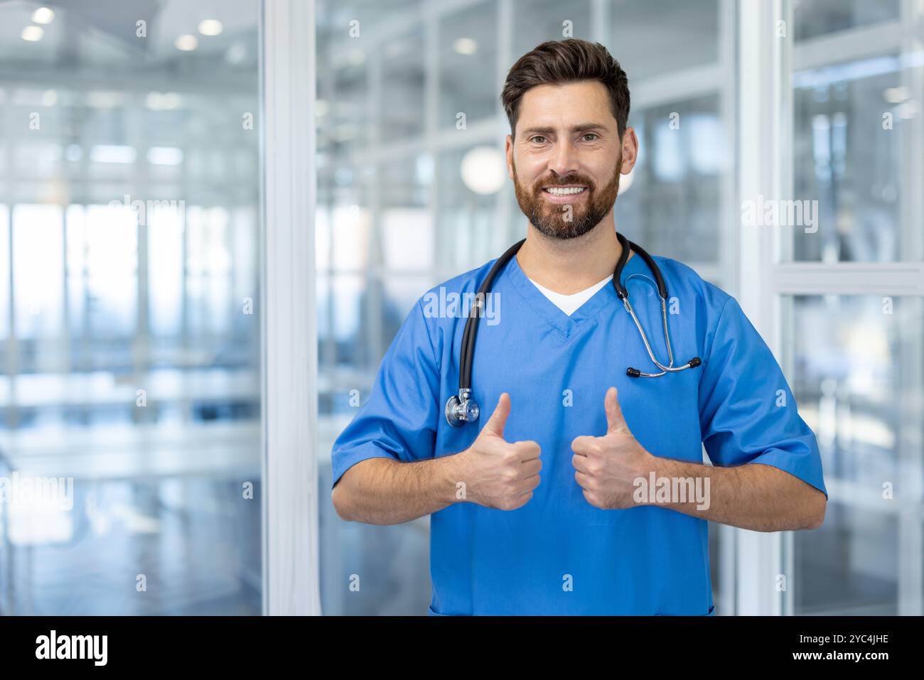 Smiling healthcare professional in blue scrubs giving thumbs up gesture ...