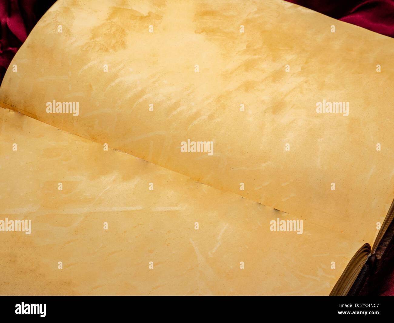 medieval old book open on a table with red velvet, aged yellowed pages ...