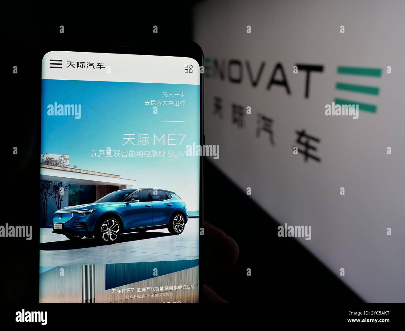 Person holding cellphone with webpage of Chinese electric car company ...