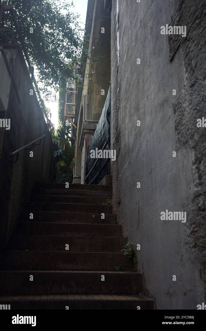 Narrow passageway made with stairs in the shade bordered by pillars of ...