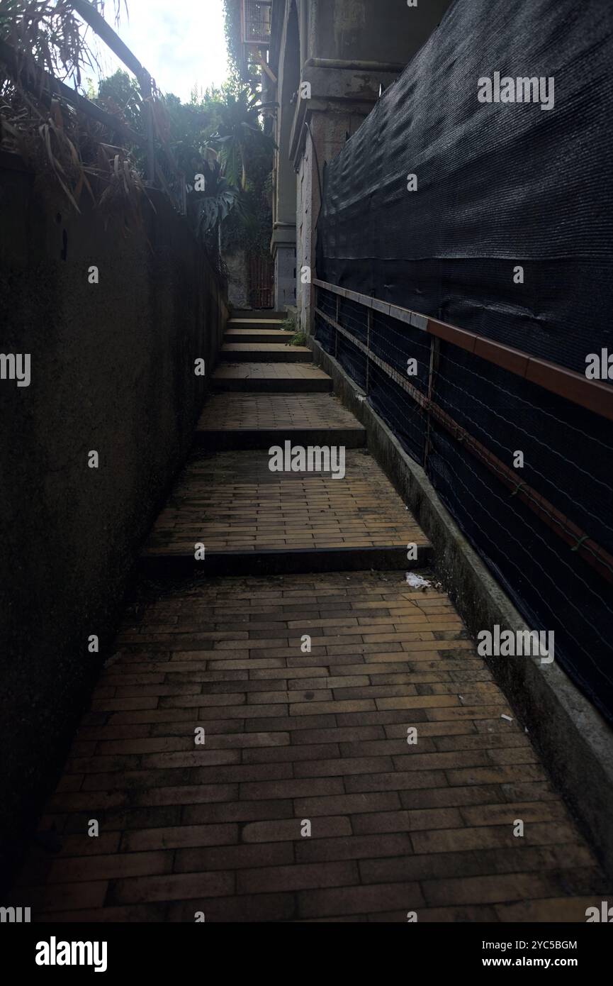 Narrow passageway made with stairs in the shade bordered by pillars of ...