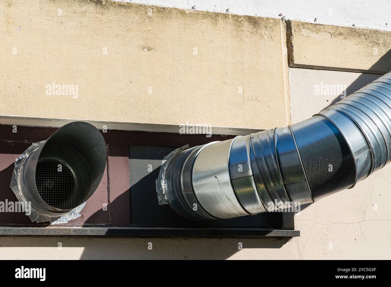 A newly installed ventilation system fixed to a building wall. One duct ...