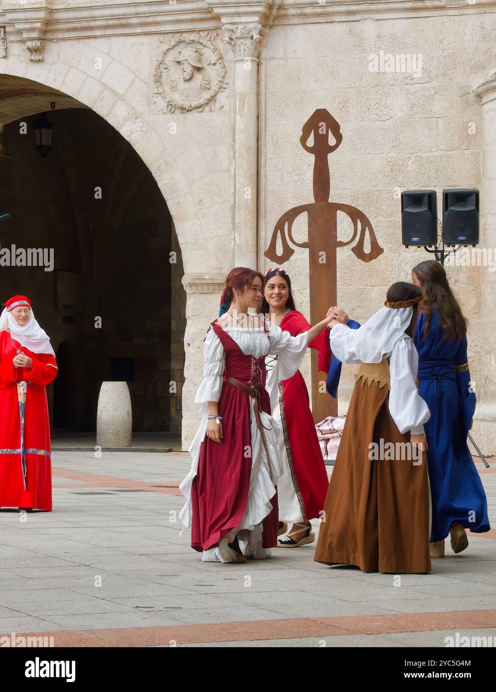 Girls in traditional costumes dancing in front of the Arco de Santa ...