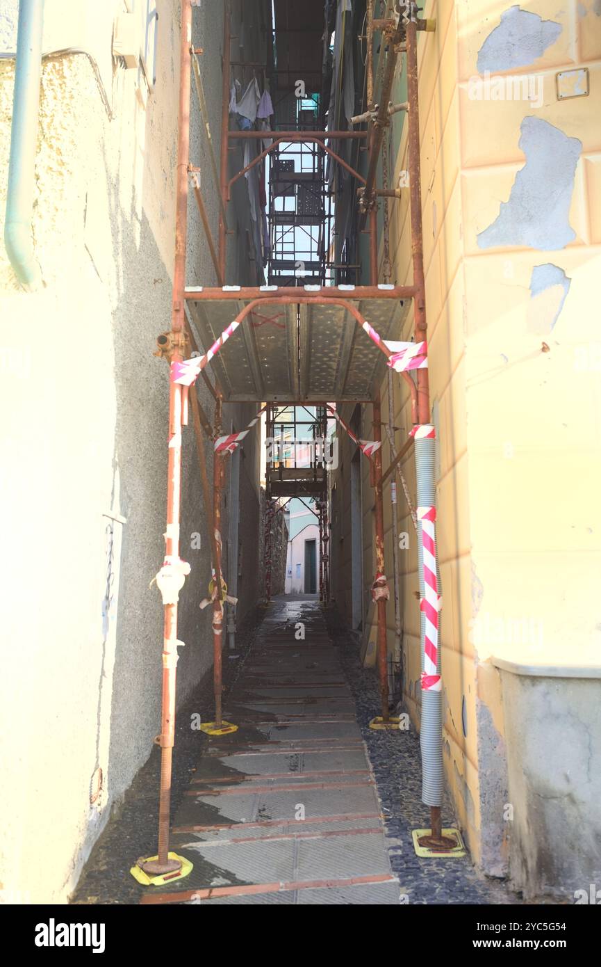 Narrow alley between tall buildings with a scaffolding Stock Photo - Alamy