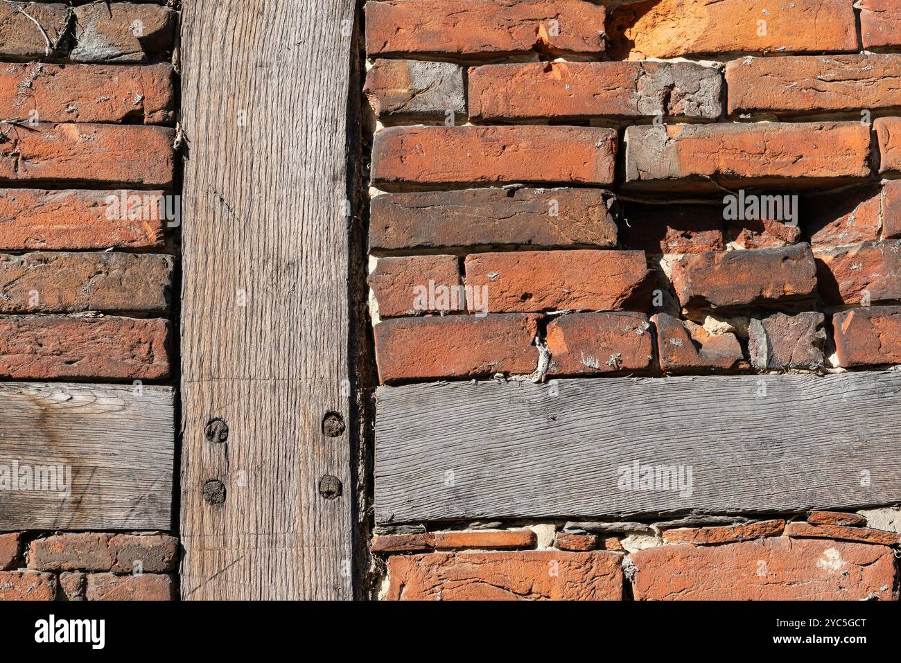 A textured wall showcases a blend of aged red bricks and sturdy wooden ...