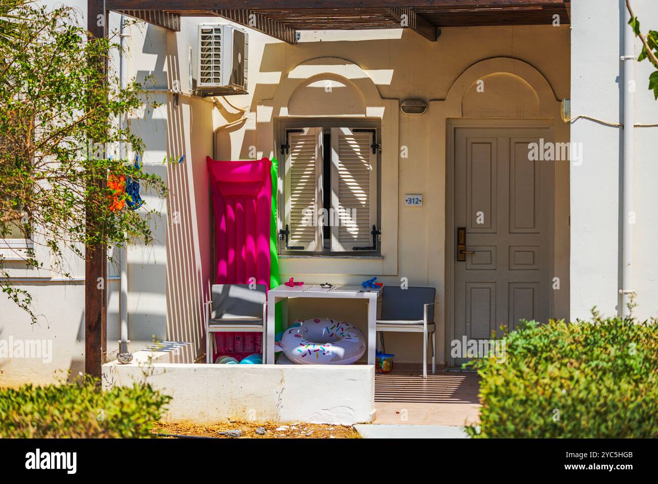 Inflatable mattress and donut float with beach items on chair and table ...