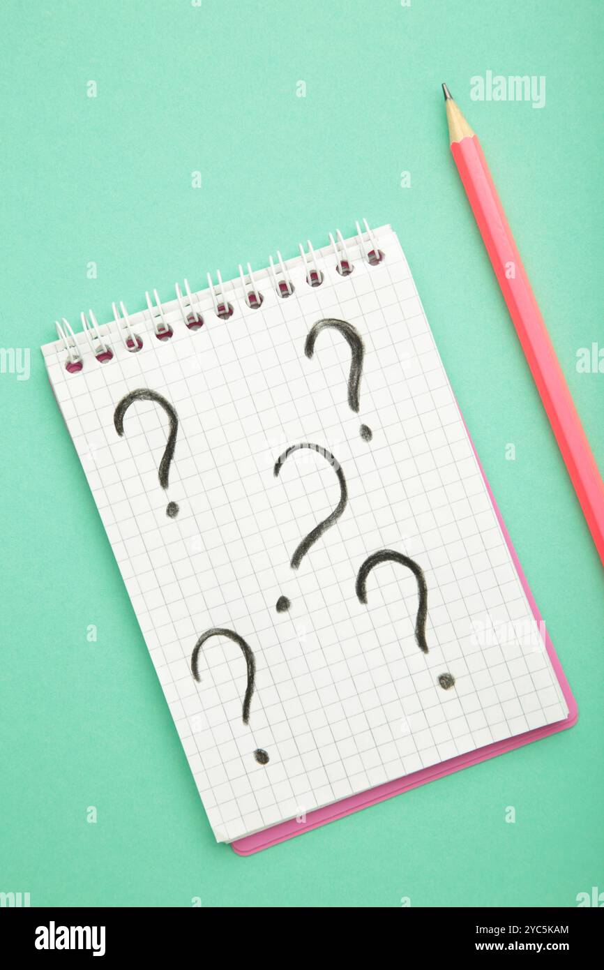 Question mark symbol on white paper with pencil on mint background, top ...