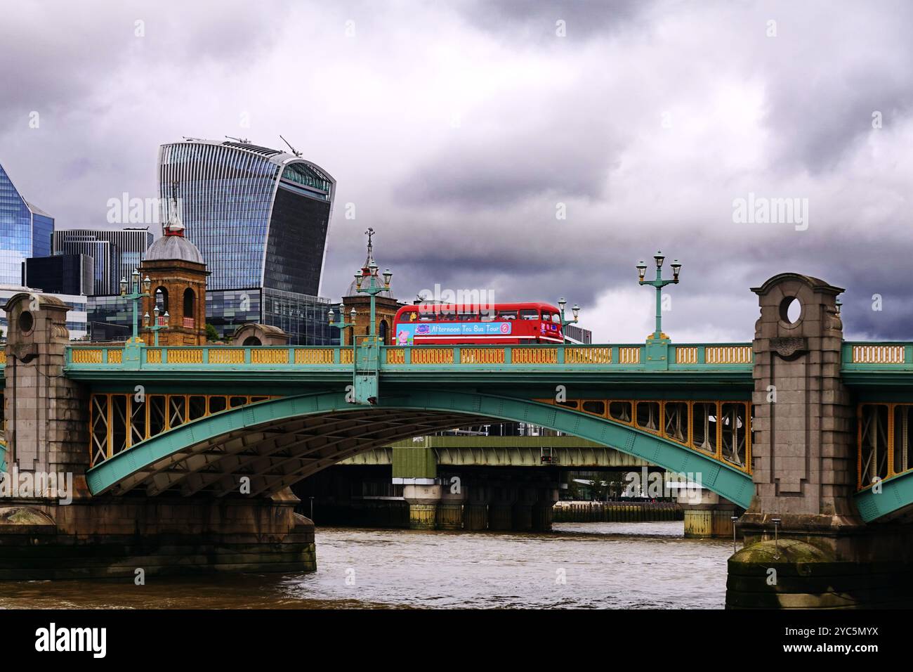Red London bus driving over Southwark Bridge, a road and foot bridge ...