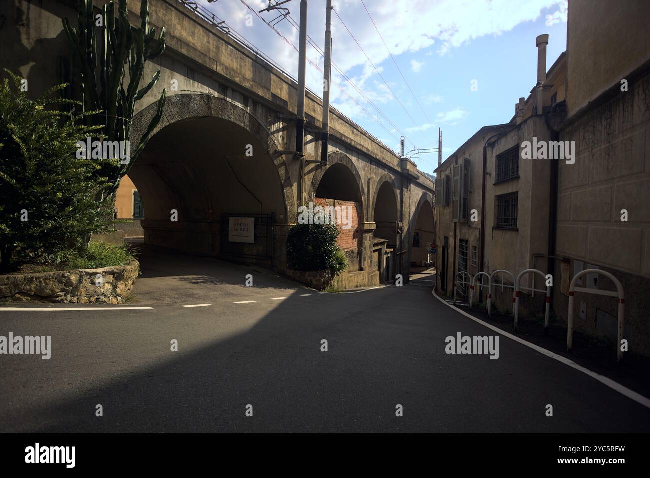 Narrow street bordered by buildings next to the arches of a viaduct in ...