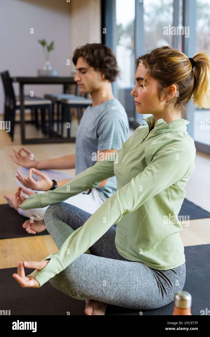 Couple meditating together on yoga mats at home, finding inner peace ...