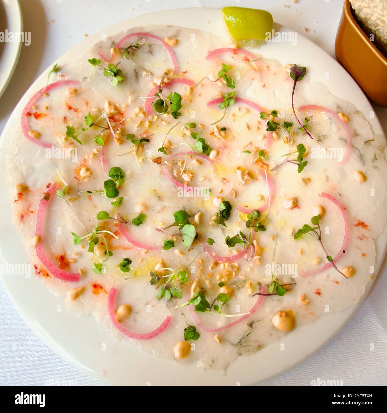 Shrimp and prawn carpaccio with peanuts lime and red curry on a round ...
