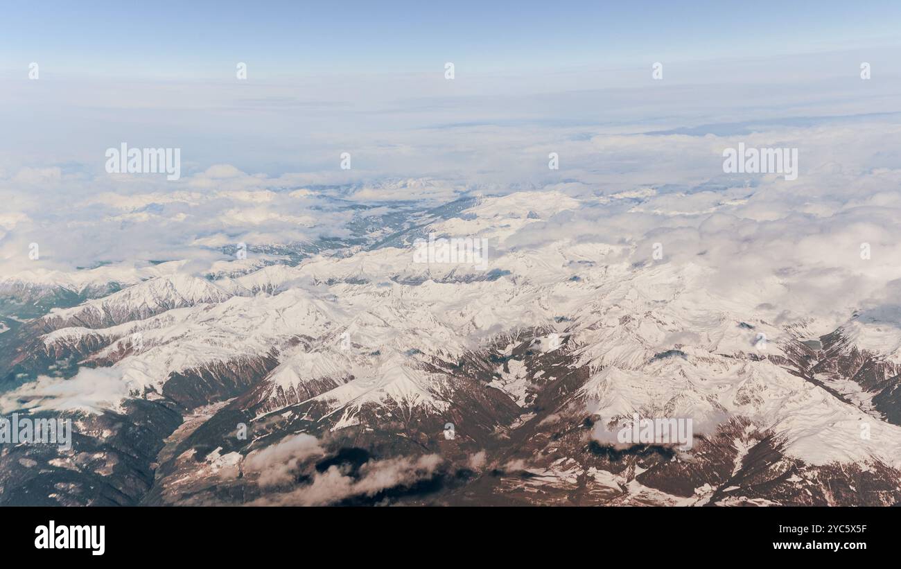 Aerial view of the snow capped Alps, with rugged mountain peaks extending across the landscape ...