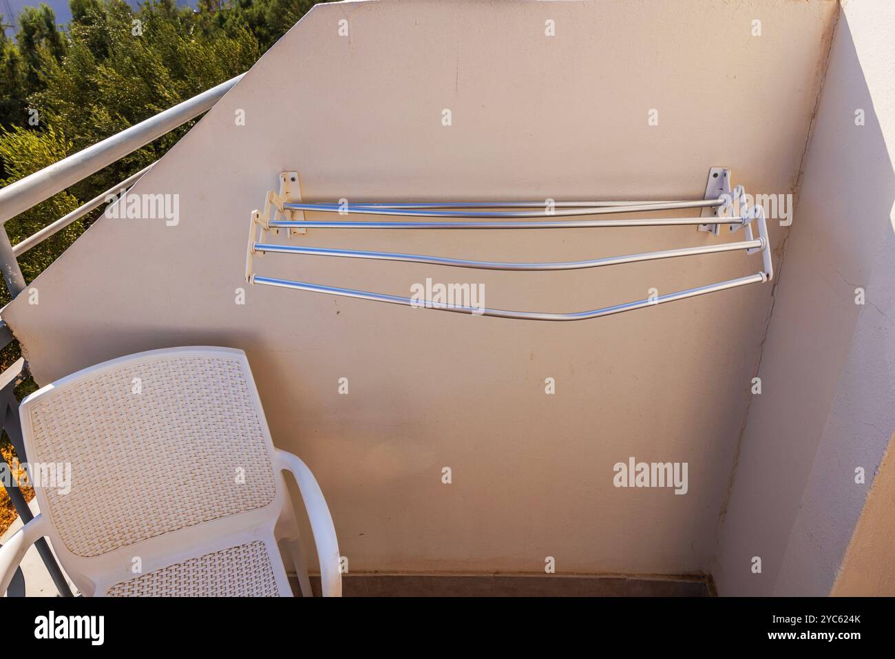 Empty wall-mounted drying rack on sunny balcony with white plastic ...