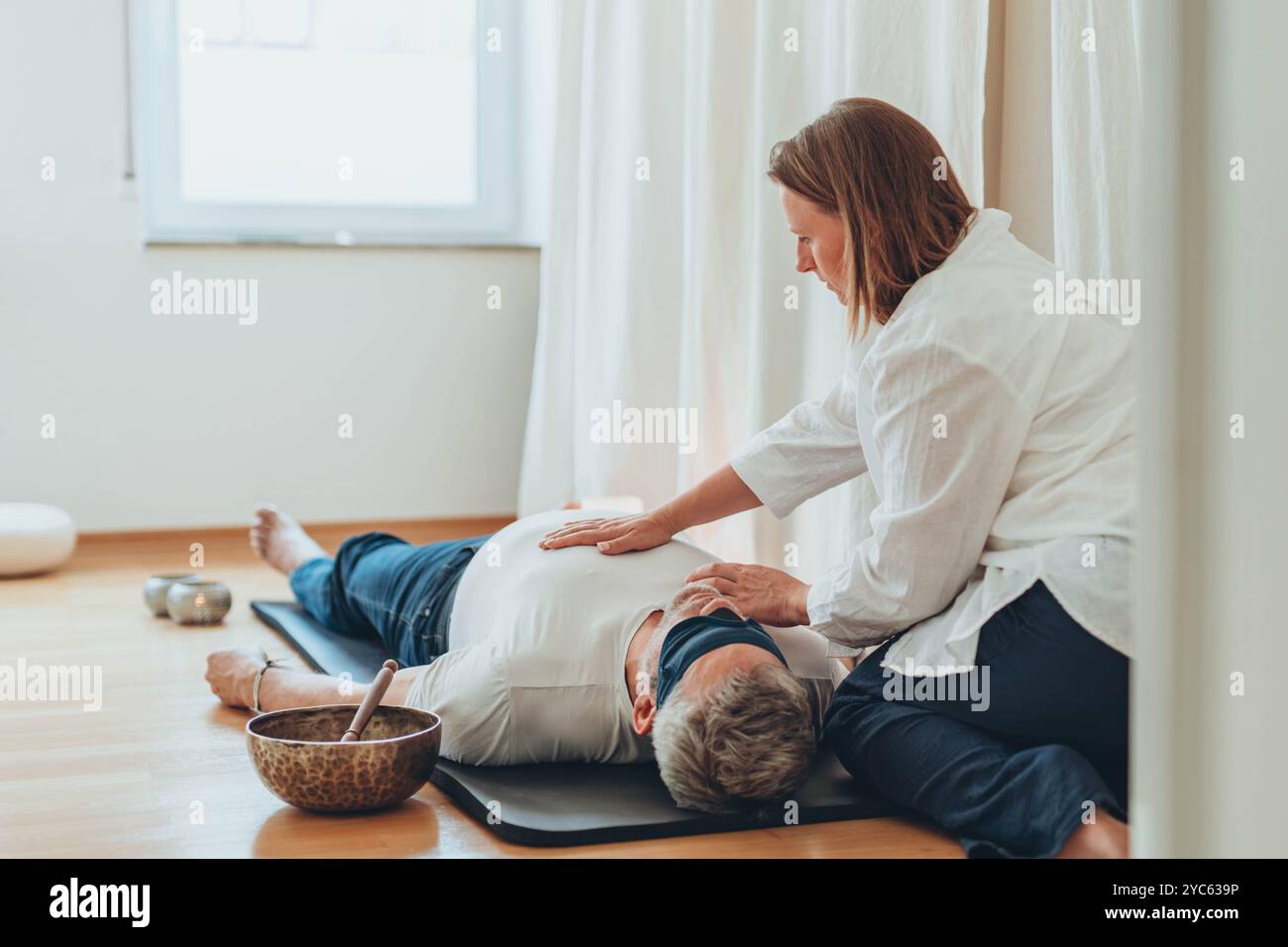 A man lying on a mat with a blindfold, practicing breathing exercises ...