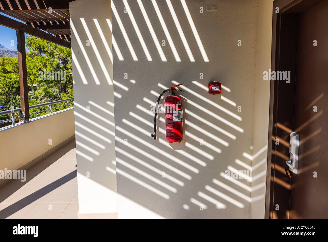 Wall hotel with red fire extinguisher and alarm button, illuminated by ...