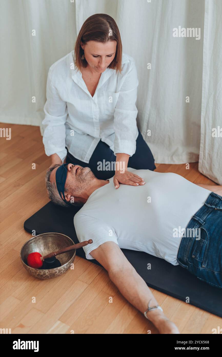 A man lying on a mat with a blindfold, practicing breathing exercises ...