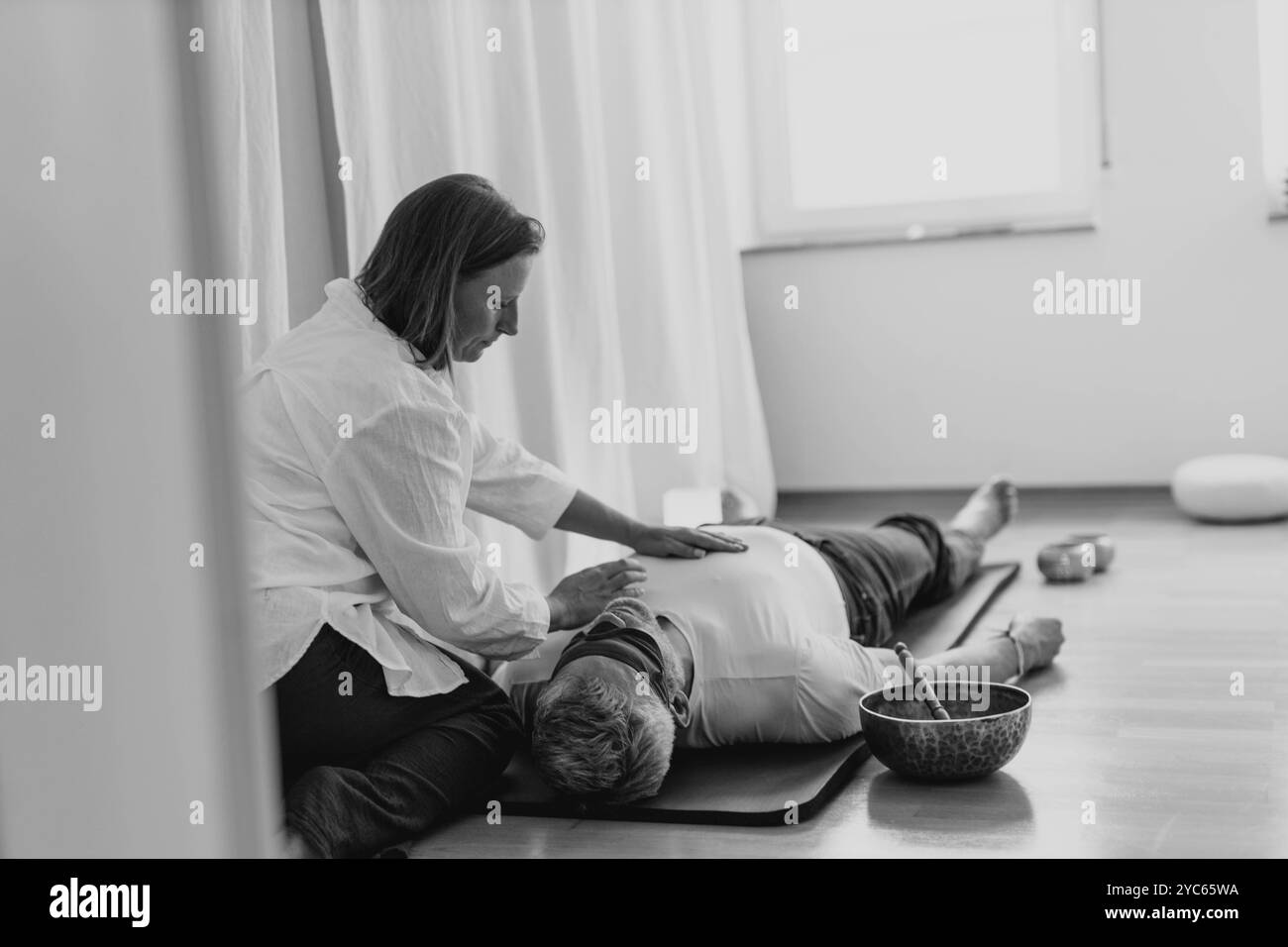 A man lying on a mat with a blindfold, practicing breathing exercises ...