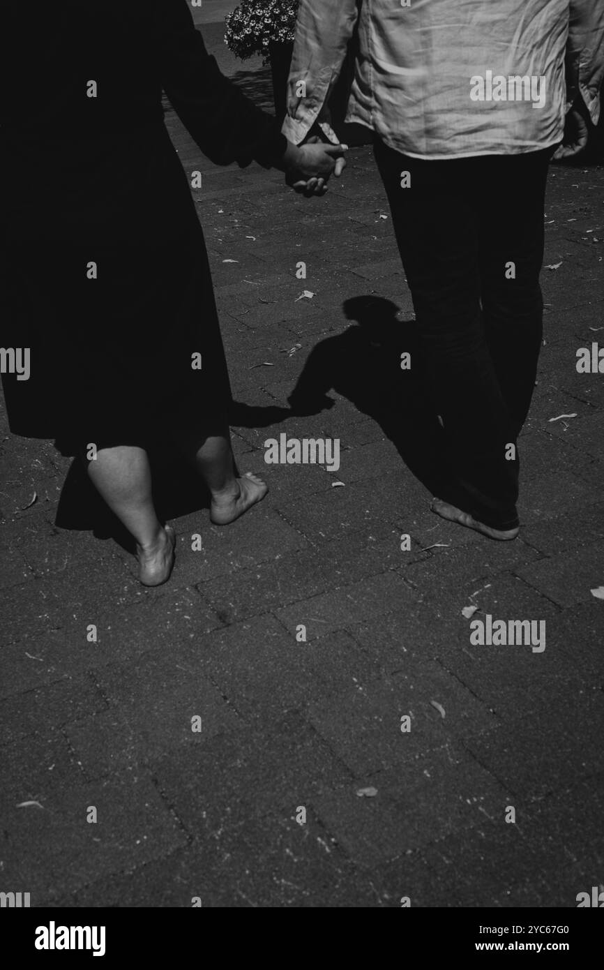 A man and a woman walking barefoot, with their shadows cast on the ...