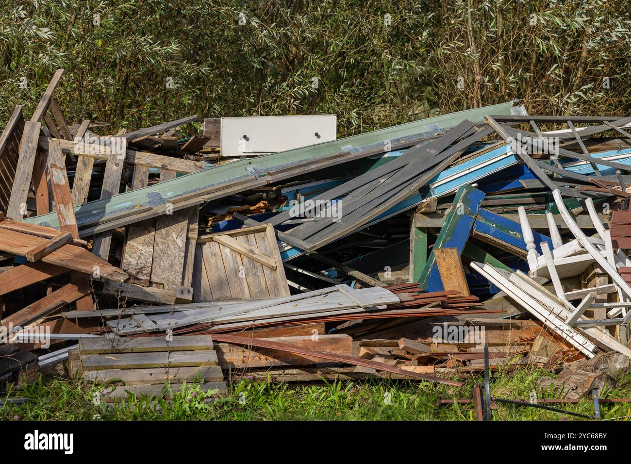 Pile of old wooden boards and discarded furniture parts in a grassy ...