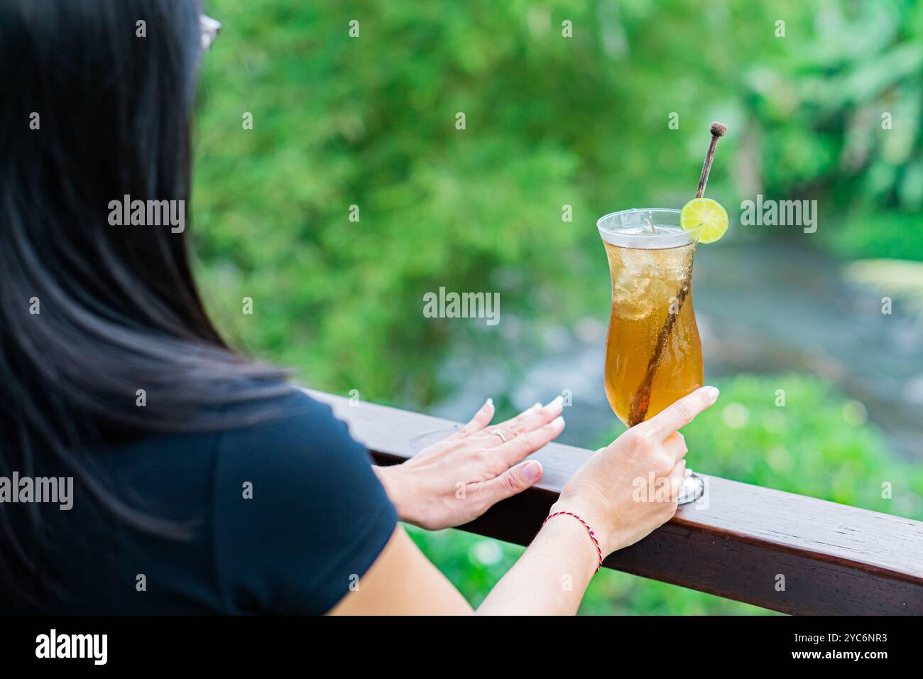 A person holding a tall glass of iced tea with a slice of lime, set ...