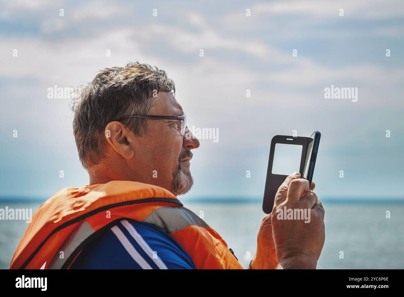 An active man in his 70s in a life jacket on a boat traveling on Lake ...