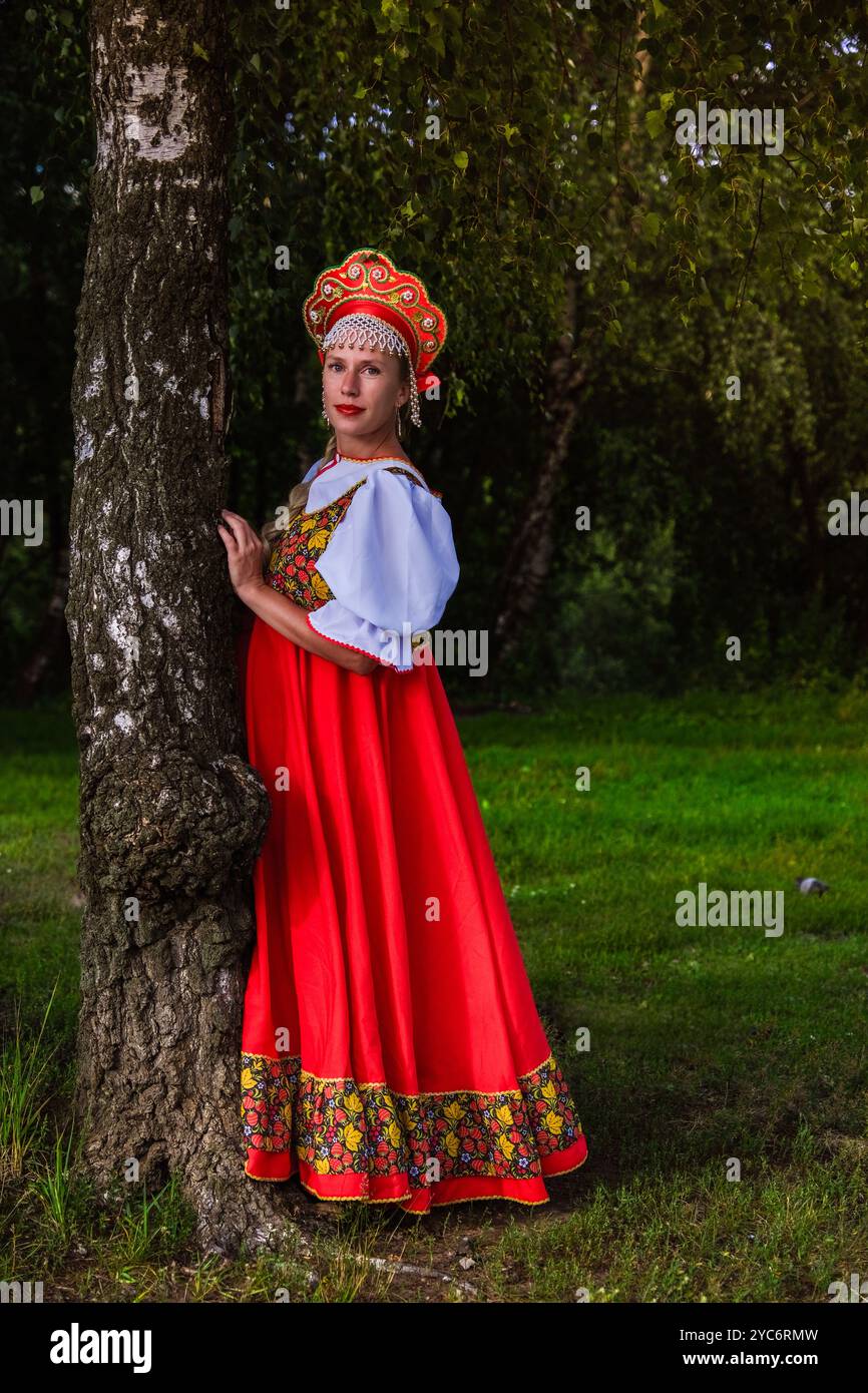 Woman in folk dress next to a tree Stock Photo - Alamy