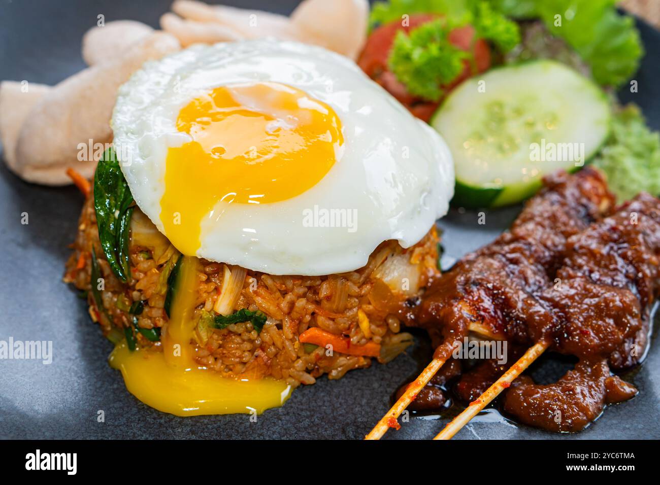 A plate of fried rice topped with a sunny-side-up egg, accompanied by ...