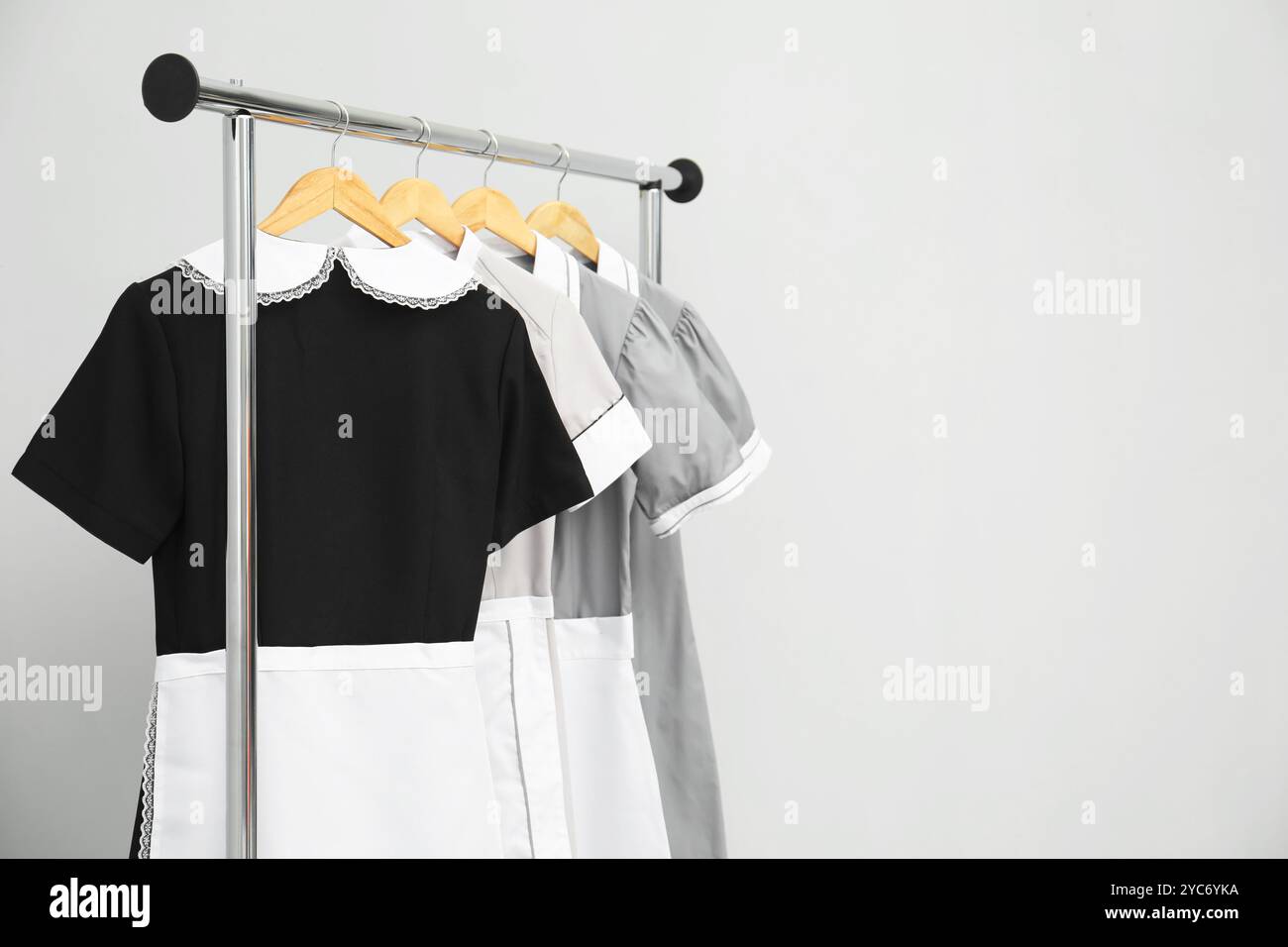 Maids' uniforms on clothing rack against grey background. Space for ...