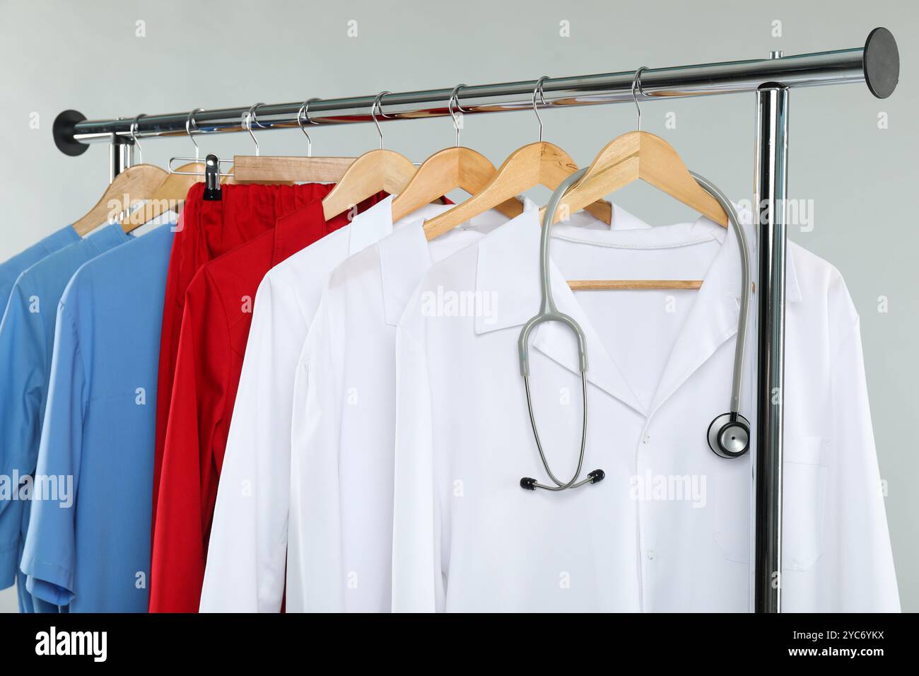 Different medical workers' uniforms and stethoscope on clothing rack ...